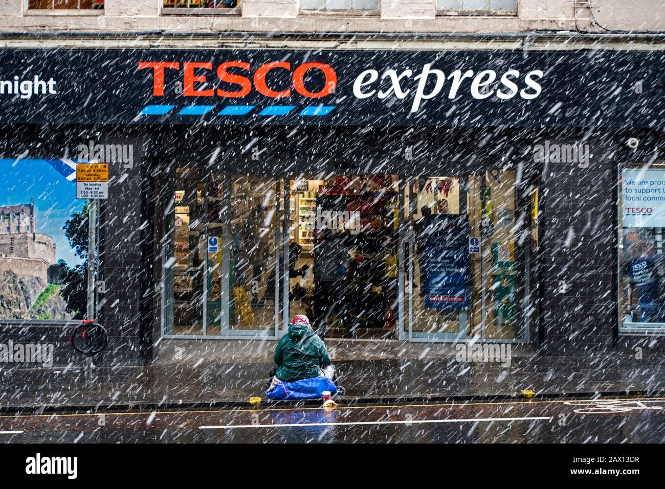 Homeless person or beggar sits begging during a blizzard outside the ...