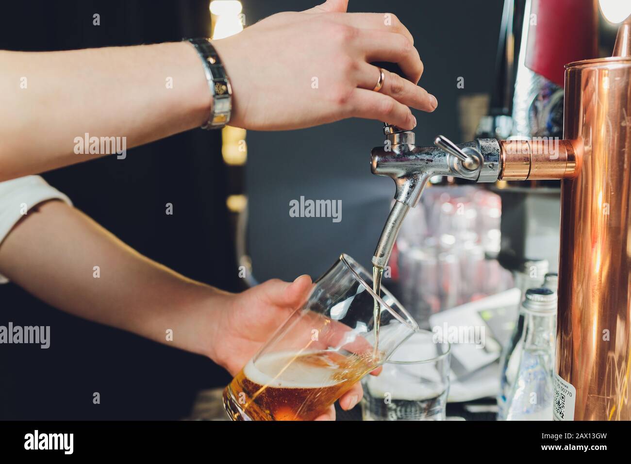 Close up of a male bartender dispensing draught beer in a pub holding a ...