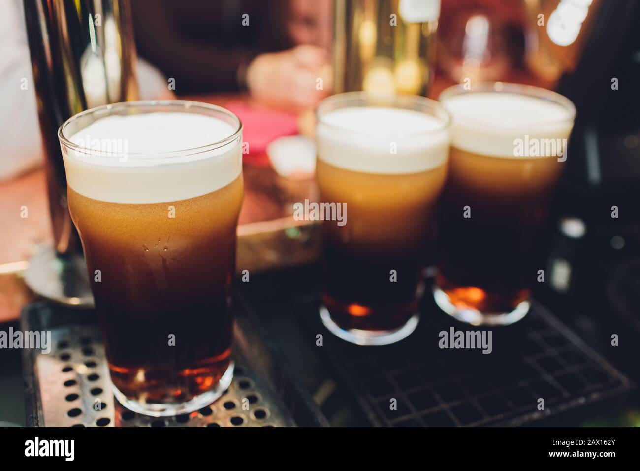 Close up of a male bartender dispensing draught beer in a pub holding a ...
