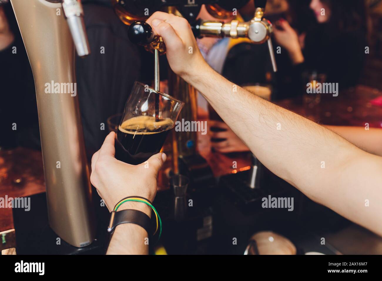Close up of a male bartender dispensing draught beer in a pub holding a ...