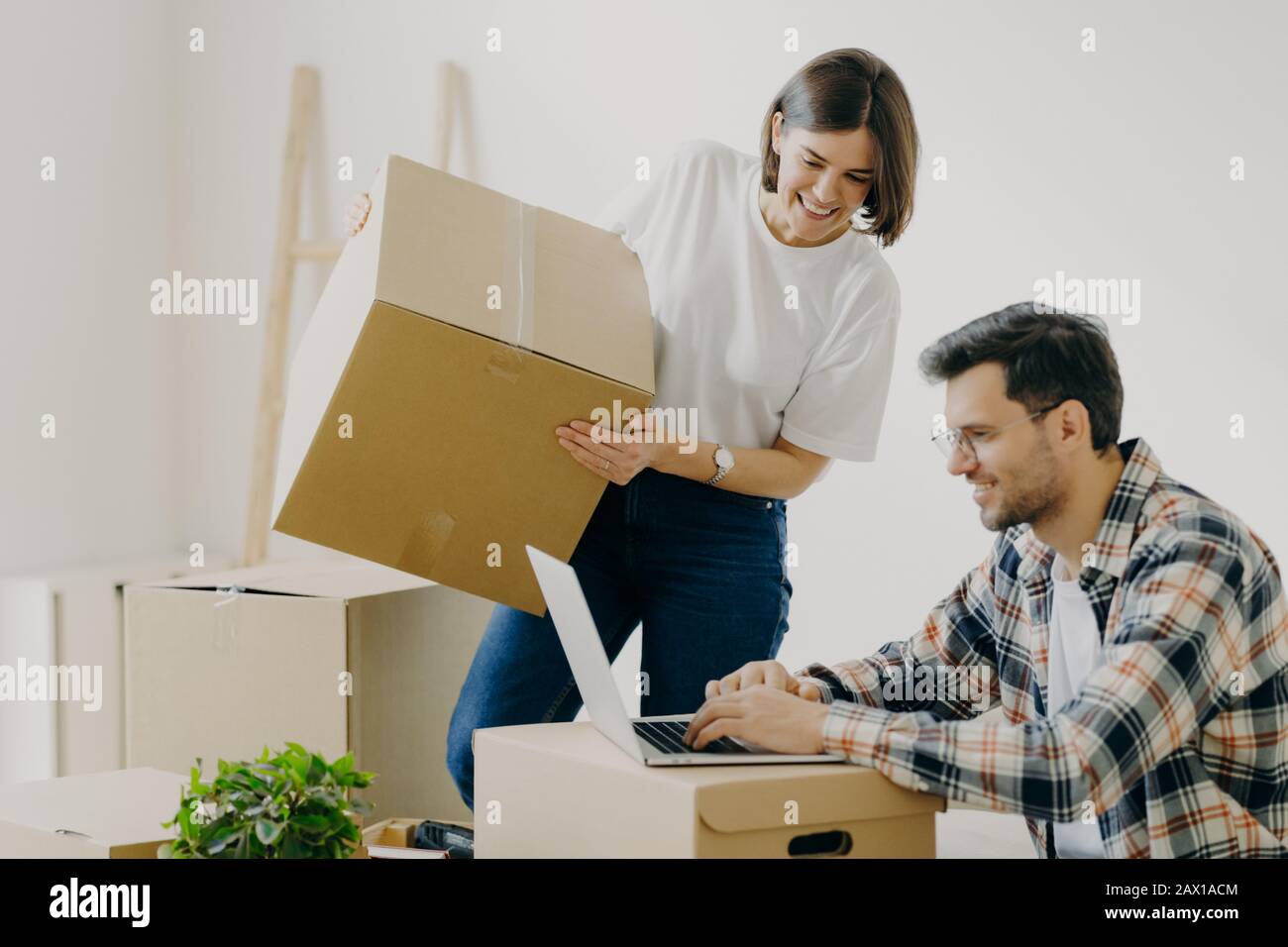 Freshly married family couple pose in their new apartment, unpack boxes ...