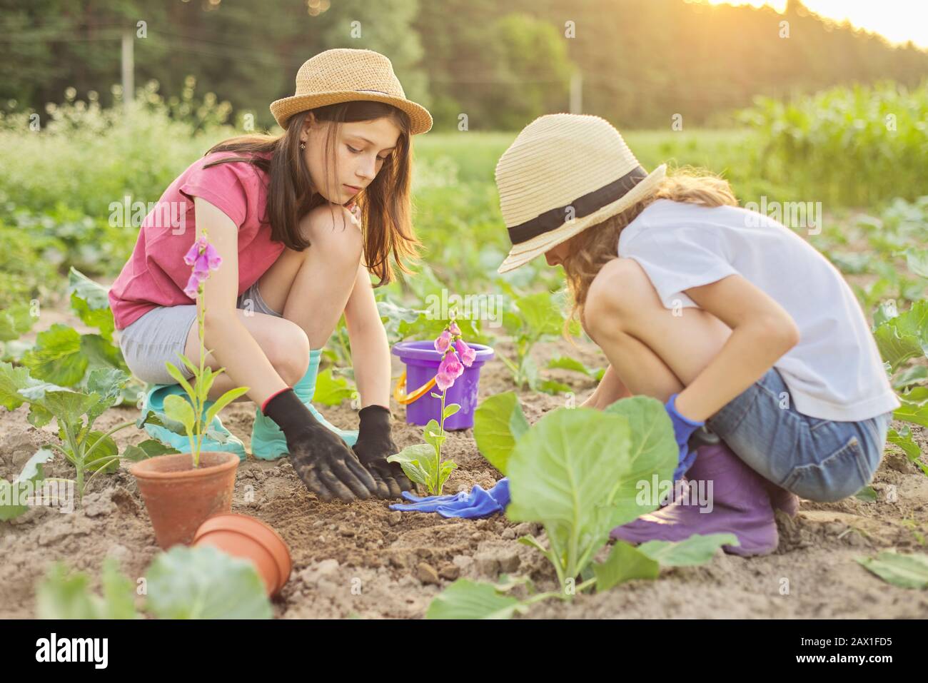 Children two girls with flowers in pots, gloves with garden tools ...