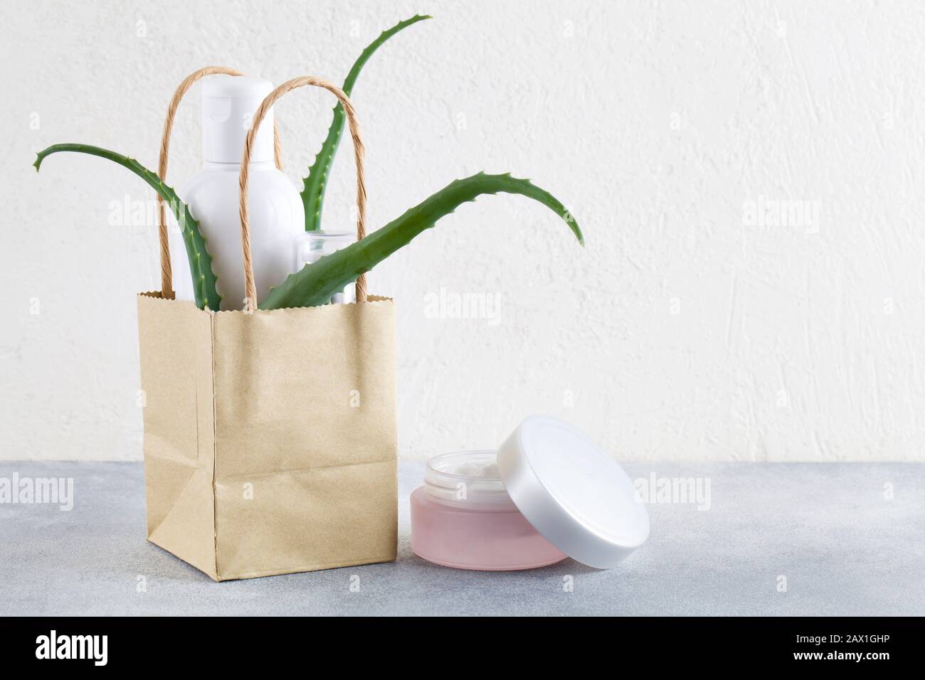 cream, paper bag with cosmetics and leaves of aloe vera on white ...