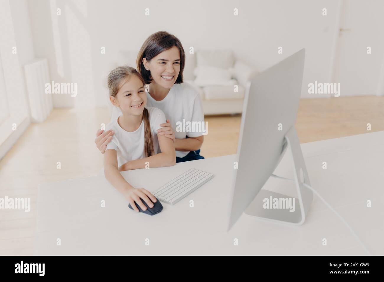 Happy brunette mother helps child do homework on computer, sit together ...