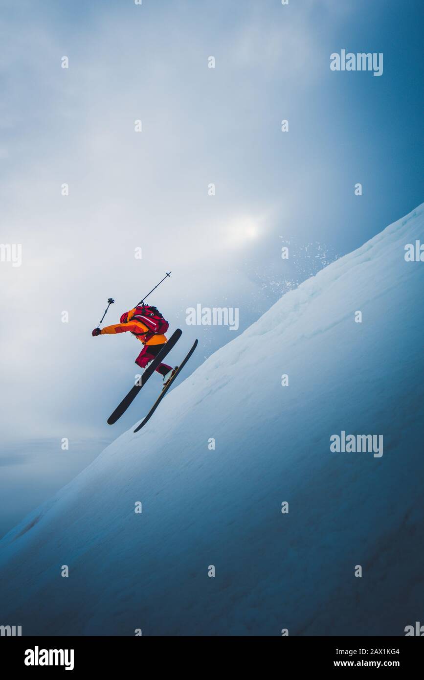 Man flying off ski jump with sun and sky behind him Stock Photo - Alamy