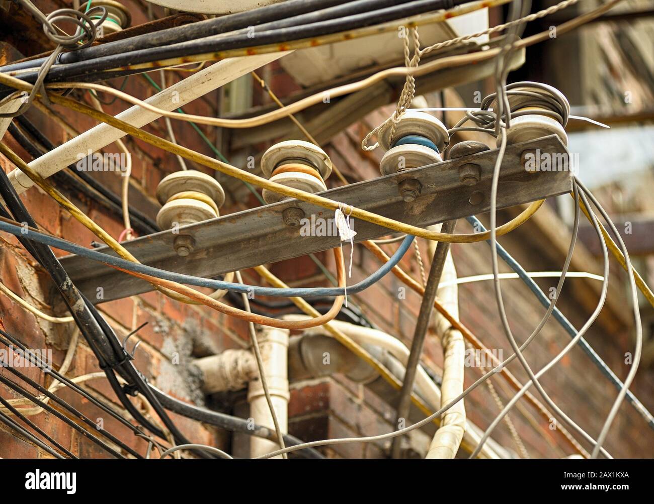 Obsolete electrical network, old wires fixed to brick building facade ...