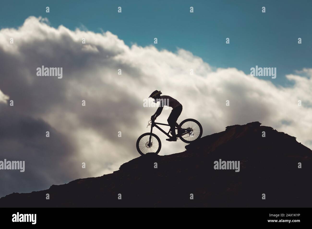 side view of young male on mountain bike riding over rocks in Utah ...