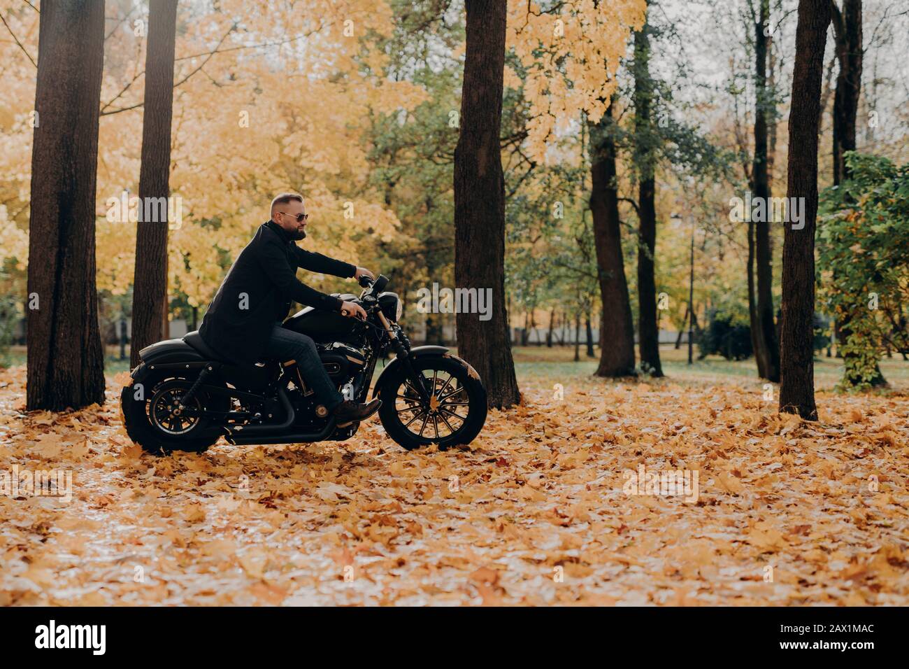 Handsome carefree bearded motorcyclist rides fast motorbike, wears ...