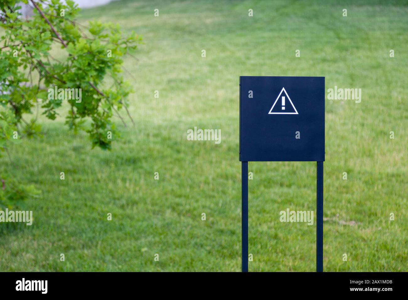 Closeup black metal sign at green grass background, nameplate with a ...