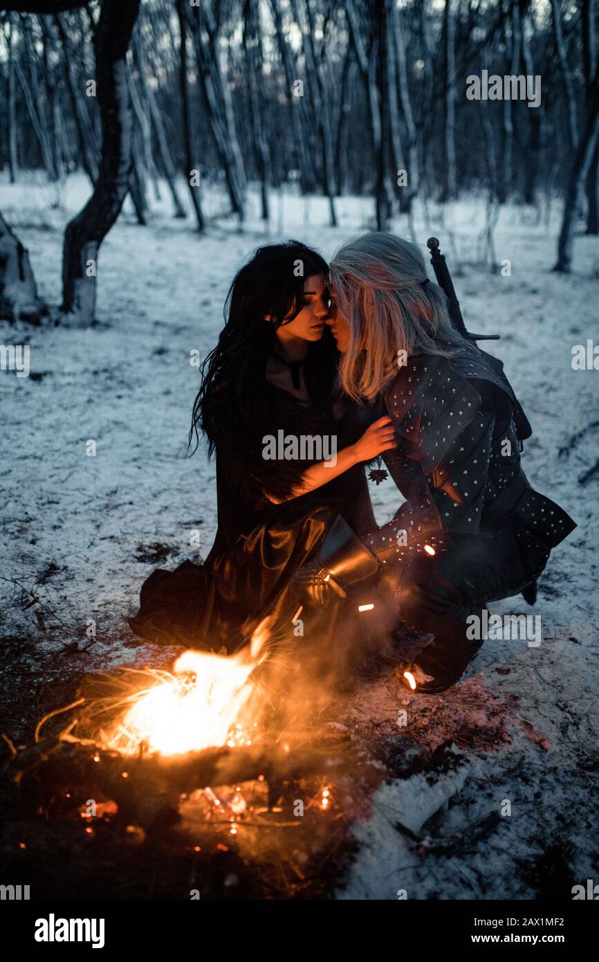 Couple in image of ancient warrior witcher and witch sits and embraces ...