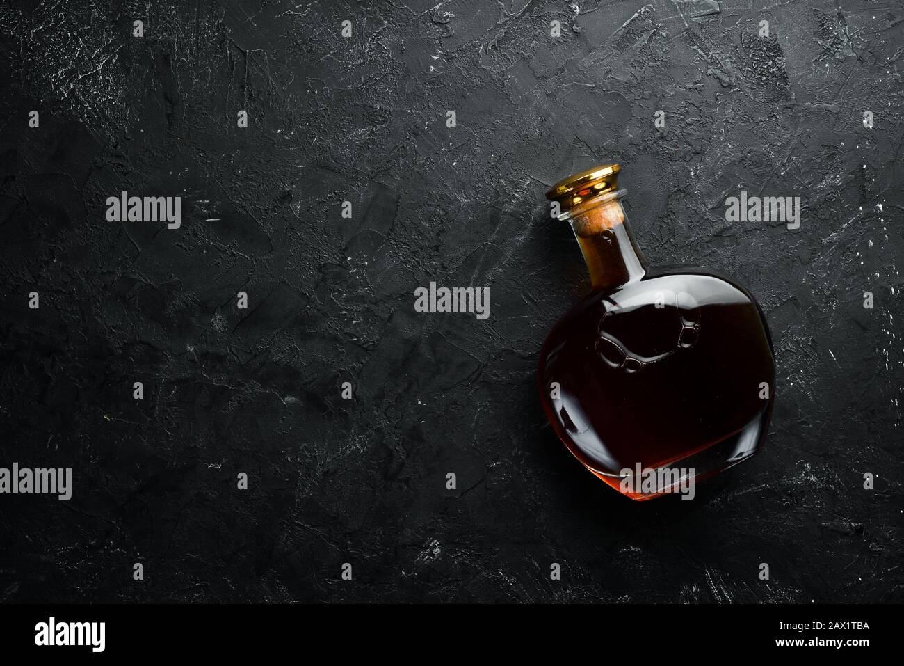 A bottle of cognac on a black background. Top view. Free space for your ...