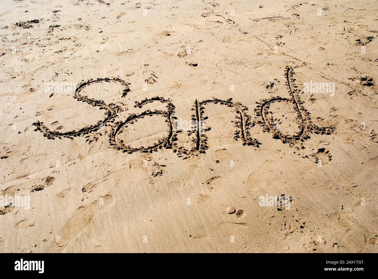 The word sand written in sand on the beach Stock Photo - Alamy