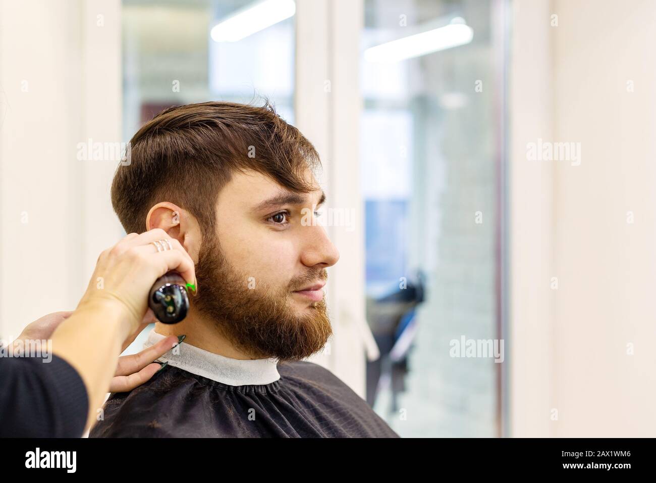 Hairdresser doing haircut for male client, man with beard using ...