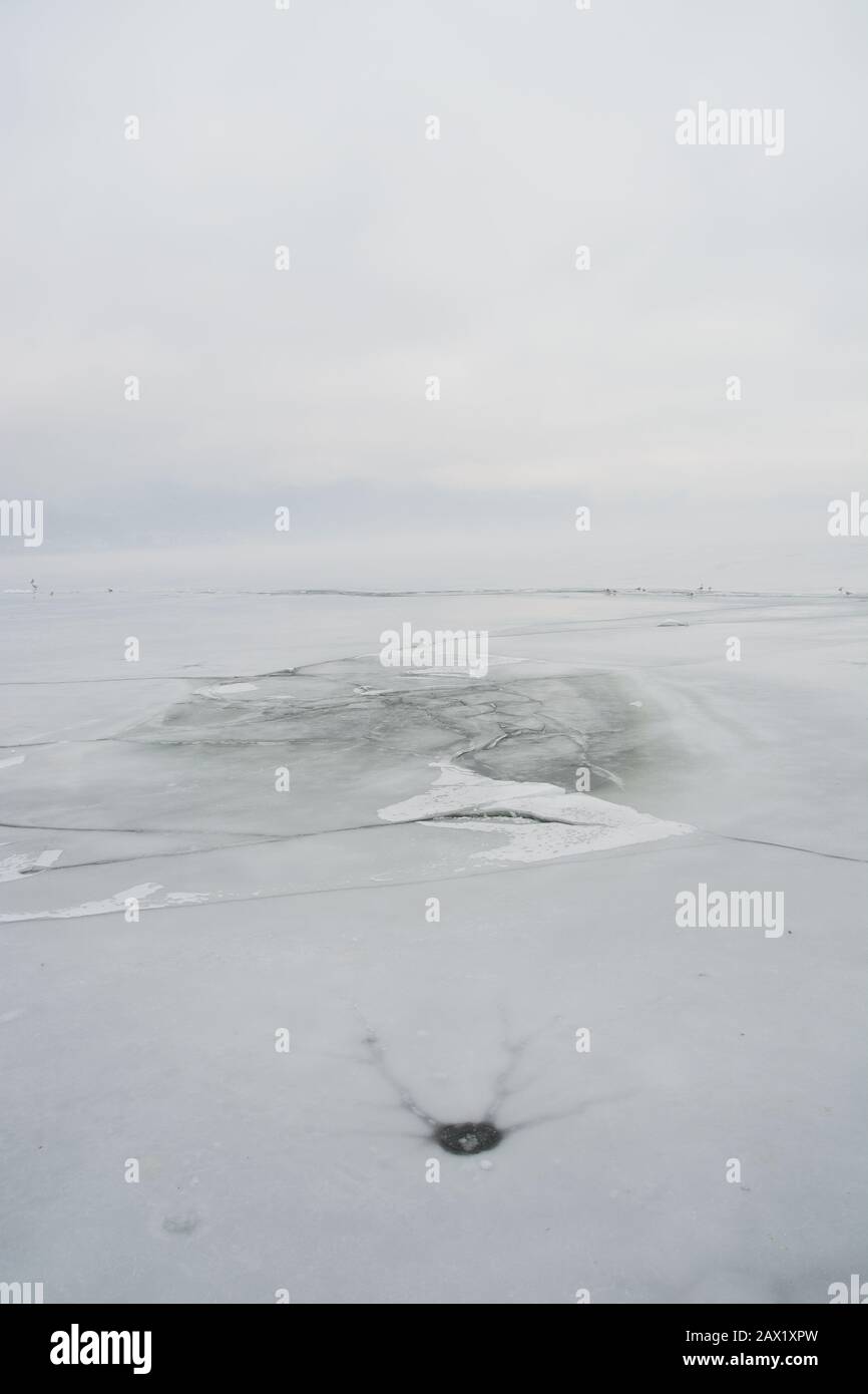Winter scenery with cracked ice on frozen lake a misty morning Stock ...