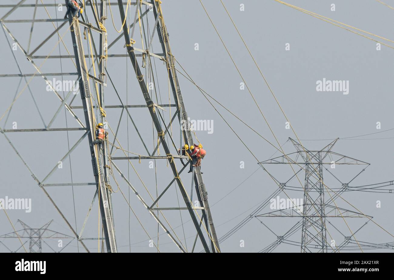 Electrical engineers climb on an overhead electricity pylon to work on ...