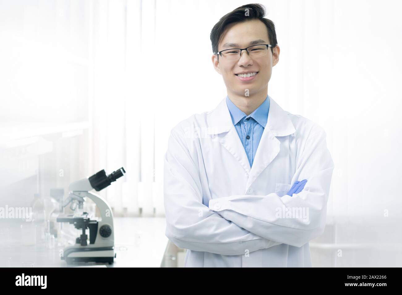 Confident Asian man wearing white lab coat and eyeglasses standing with ...
