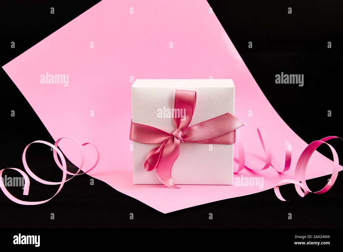 Present box with pink ribbon on the pink and black background Stock ...