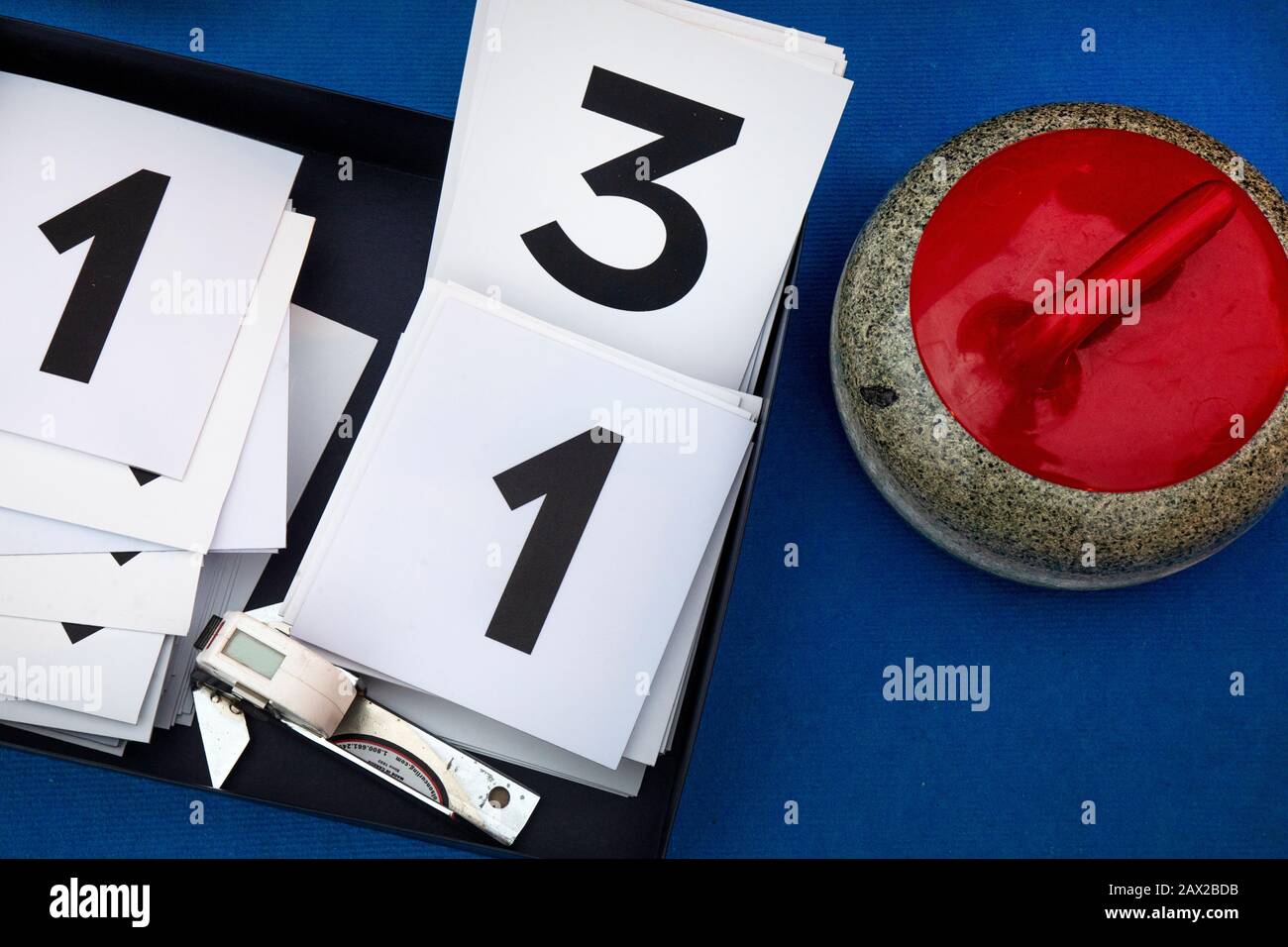 Curling red stone and score cards an ice rink field during Curling ...