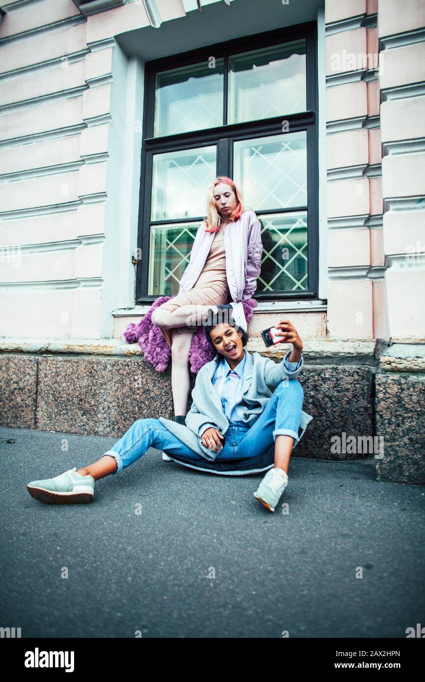 Two teenage girls infront of university building smiling, having fun ...