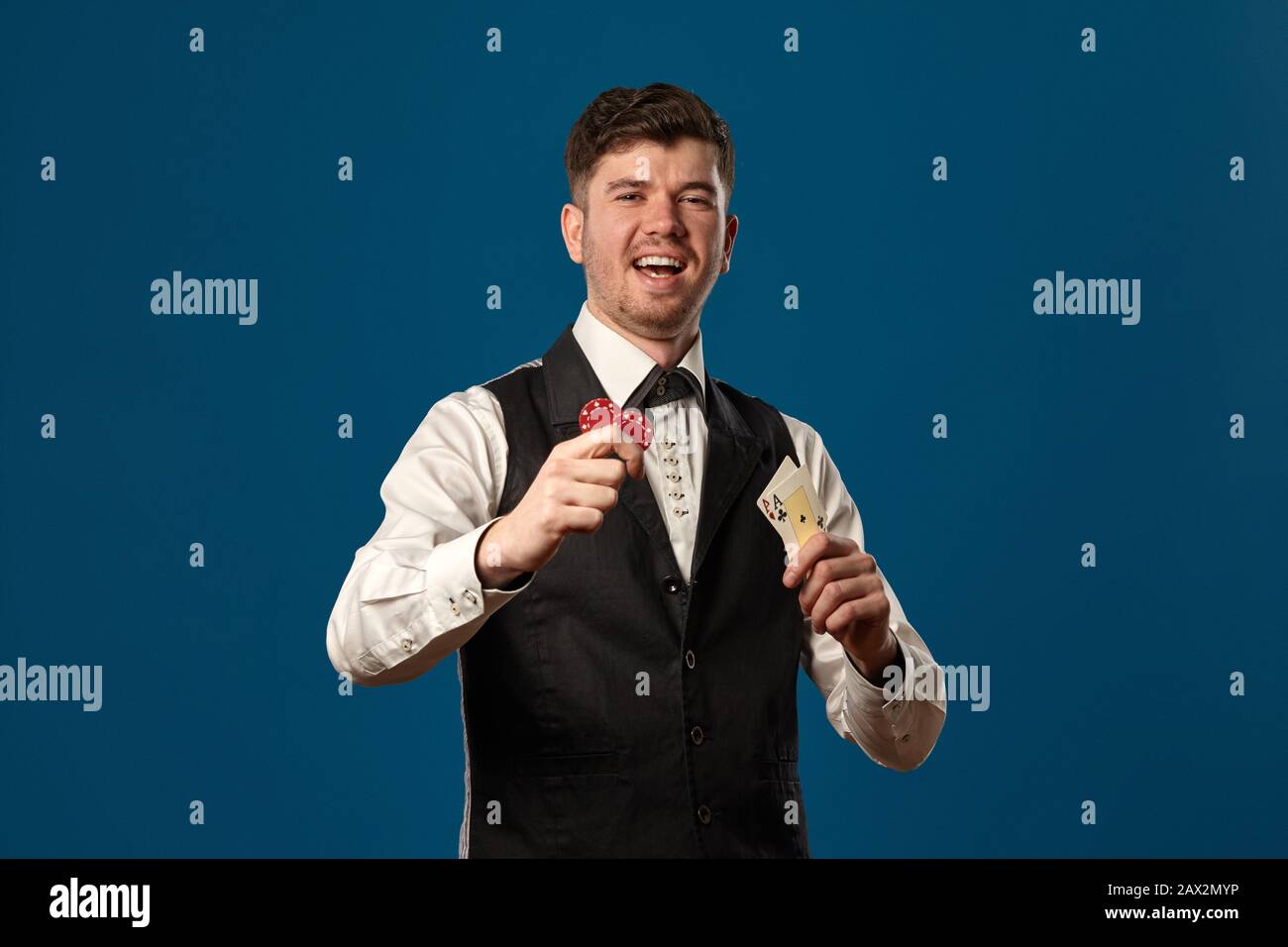 Young male, noob in poker, in black vest and white shirt. Holding two ...