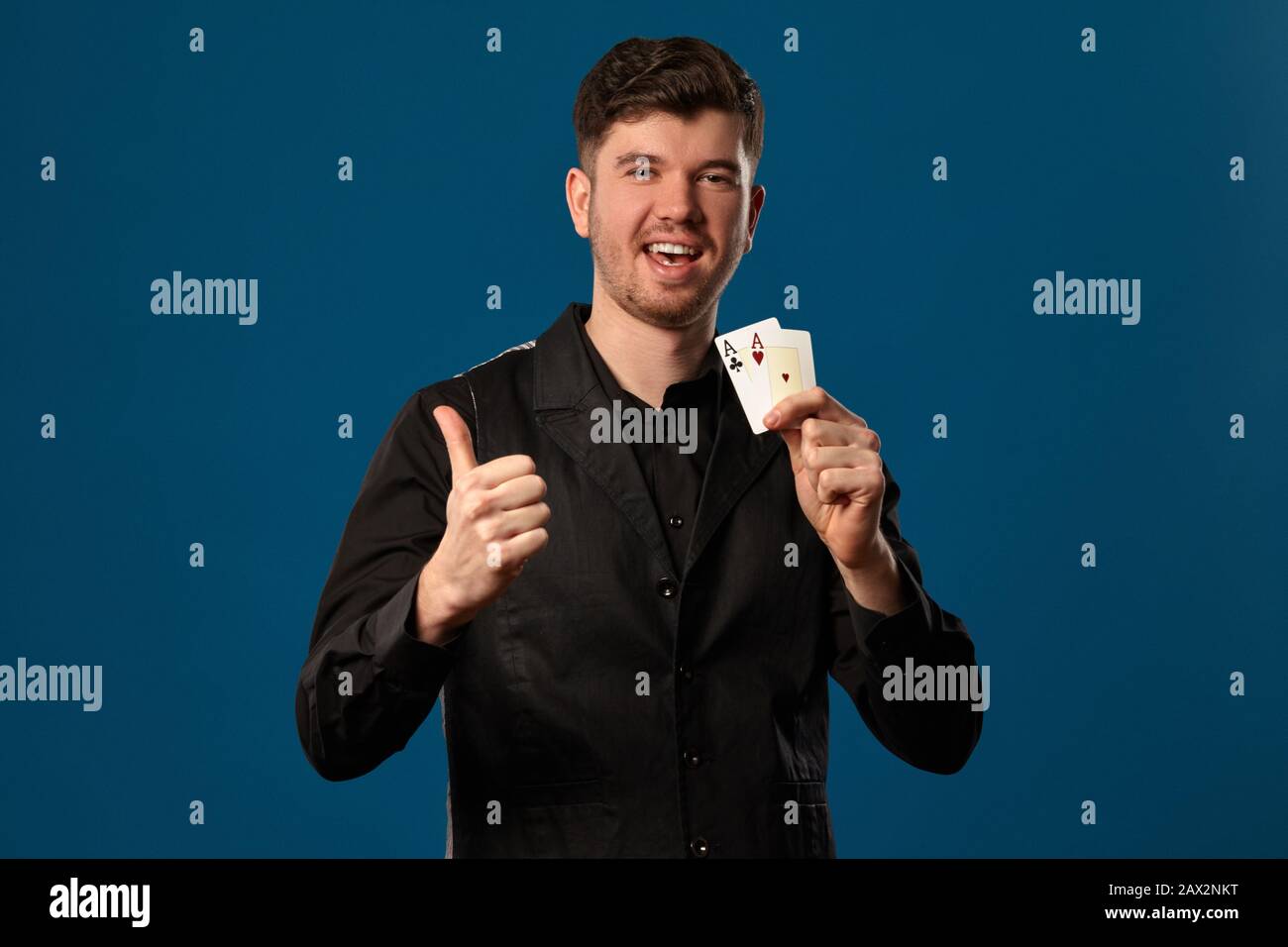 Good-looking male, noob in poker, in black vest and shirt. Holding two ...
