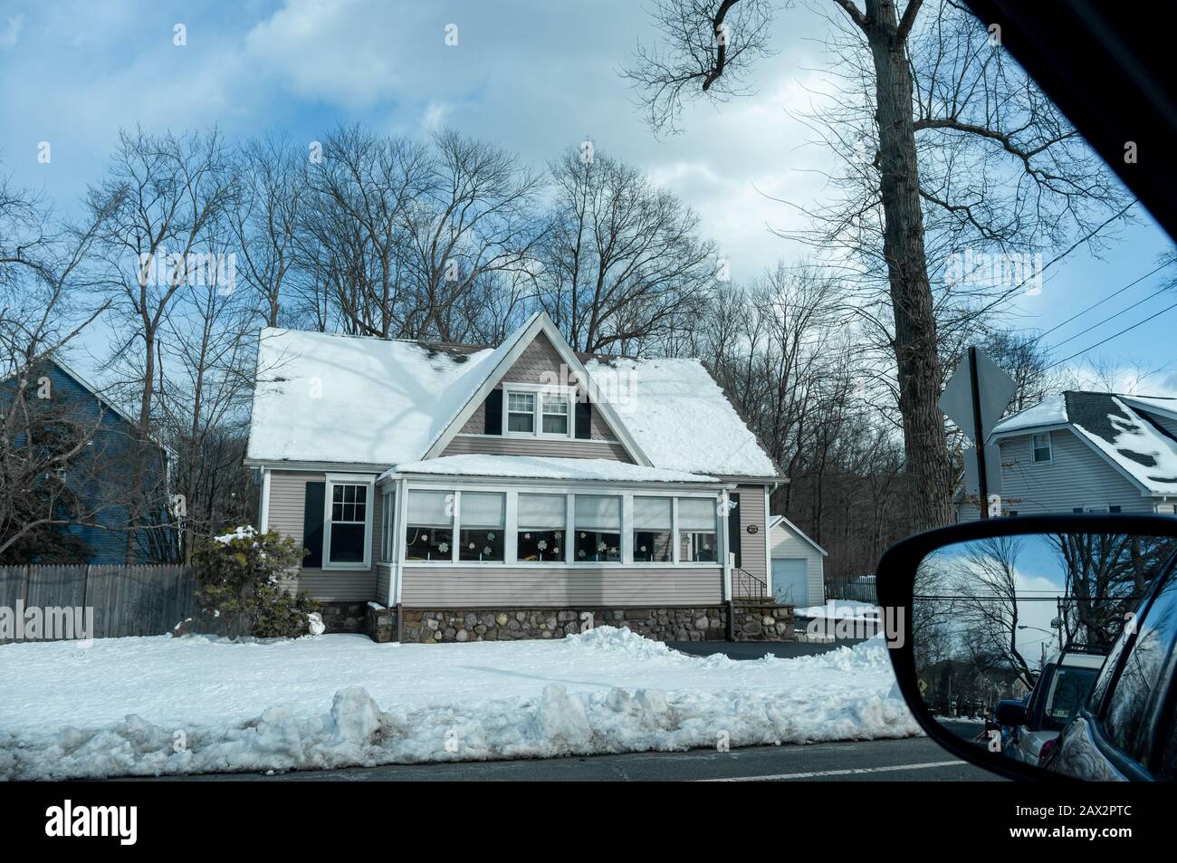passing a classic white suburban house in the snow while driving on a ...