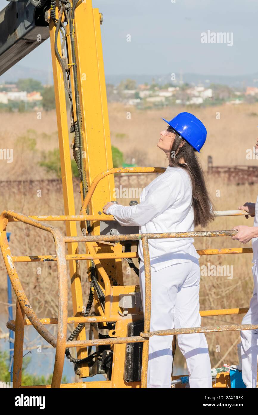 Beautiful focused woman wearing safety glasses and helmet operating the ...