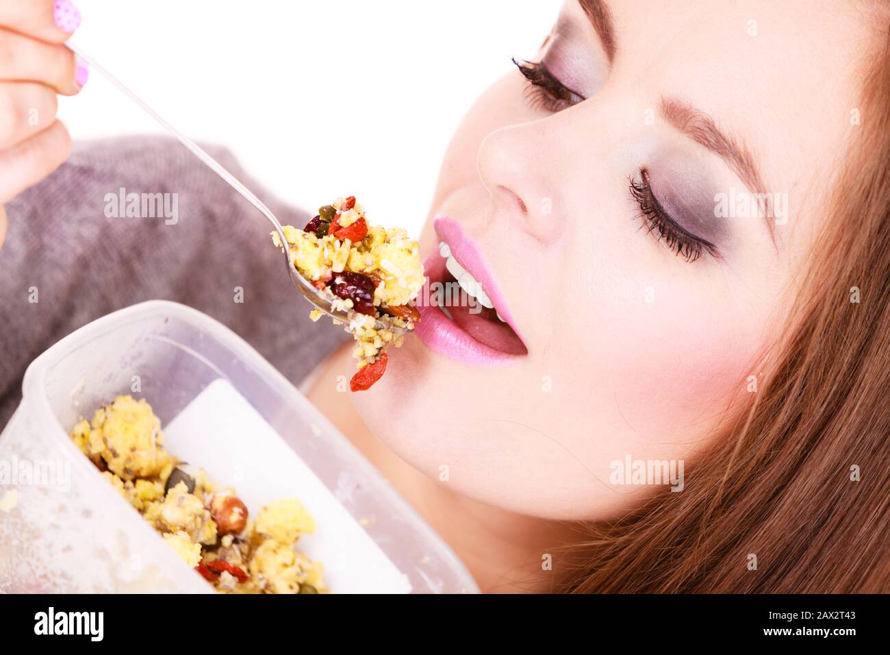 Woman eating oatmeal with nuts and dried fruits for breakfast. Girl ...