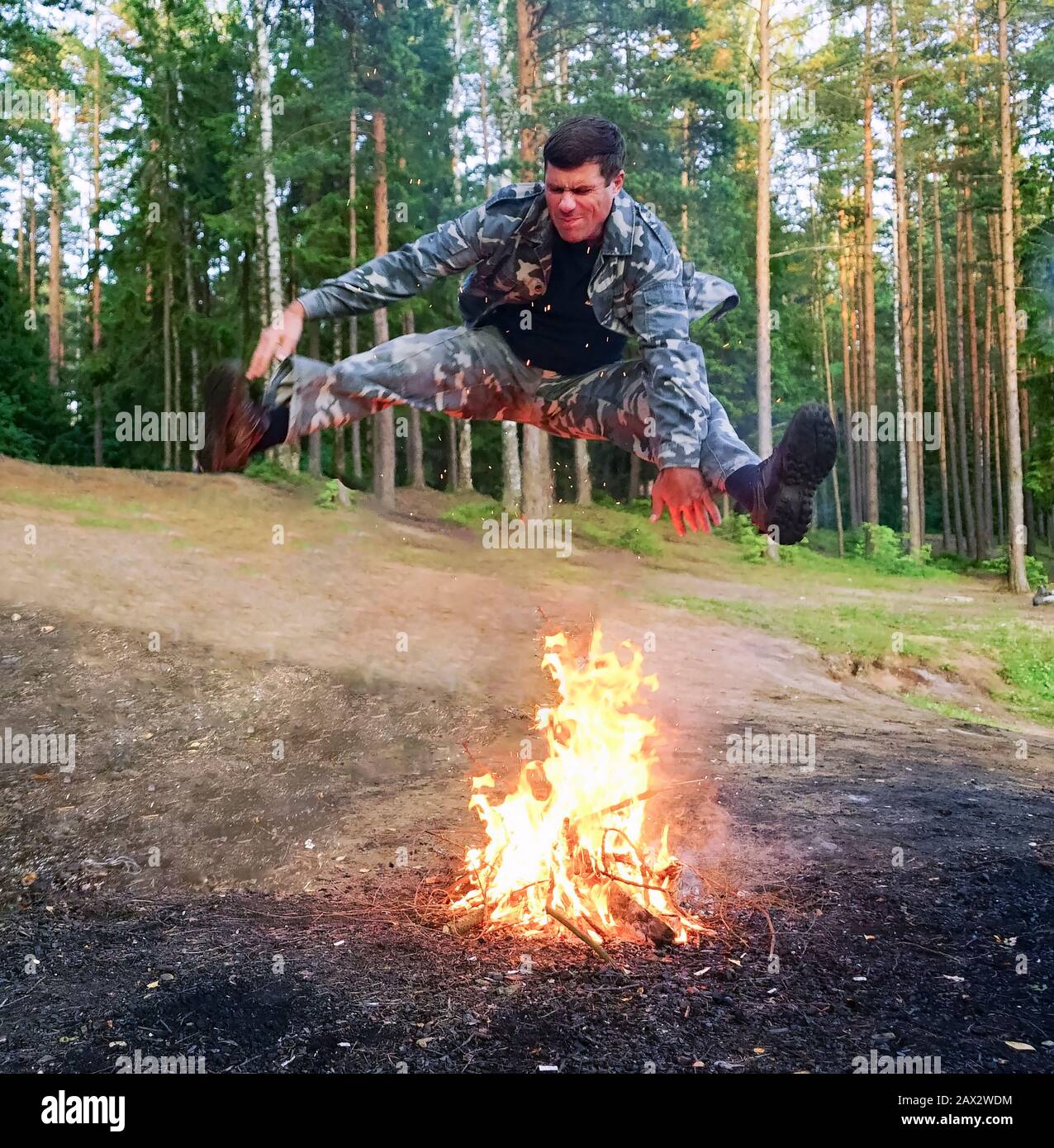 A young man in a jump over a burning fire on the lake shore Stock Photo ...
