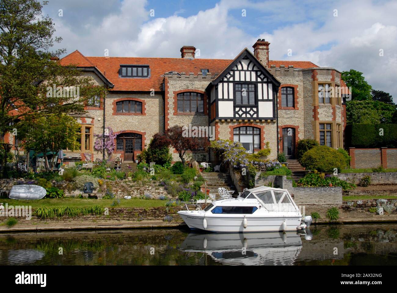 Attractive house by the river Thames, England, with small white boat ...