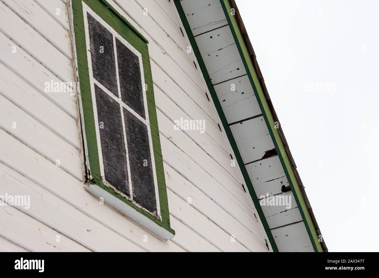 A fake window on the side of a wooden house is made out of wood and ...