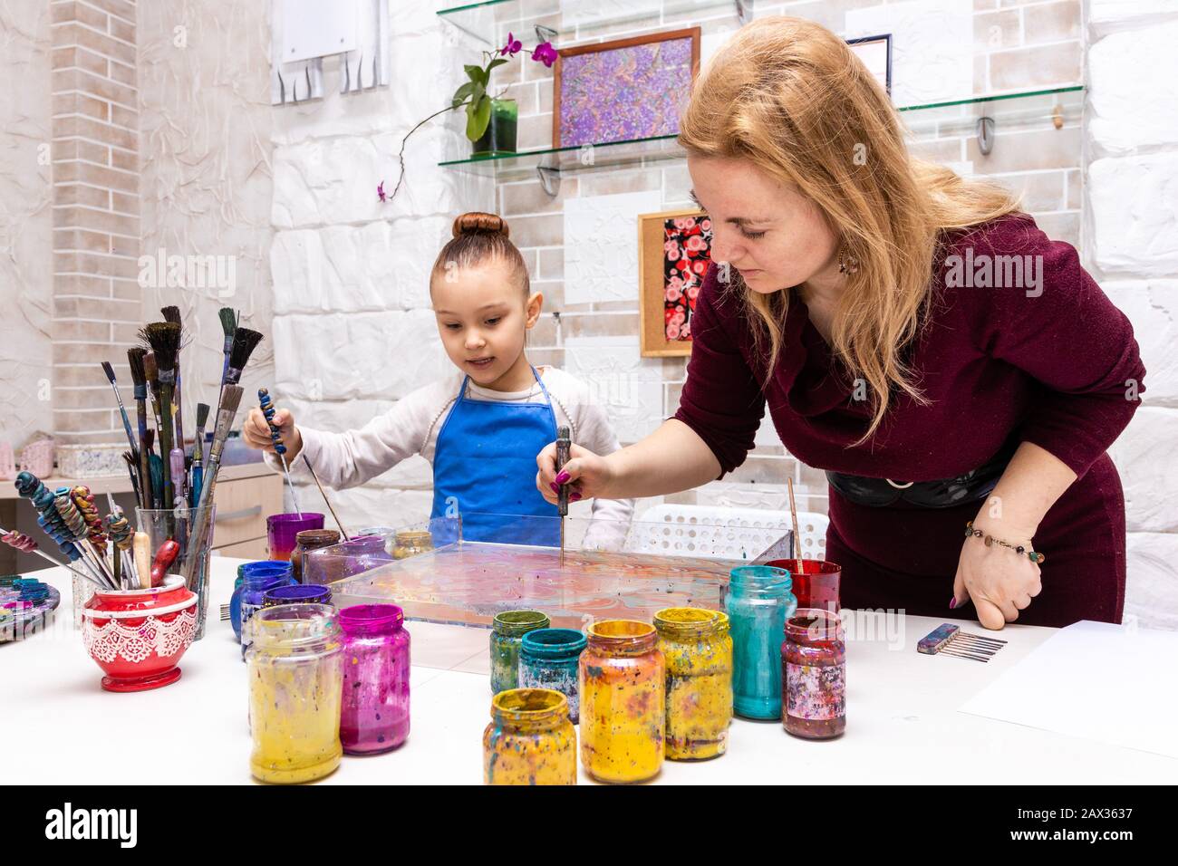 female teacher shows girl methods of transferring images on paper ...