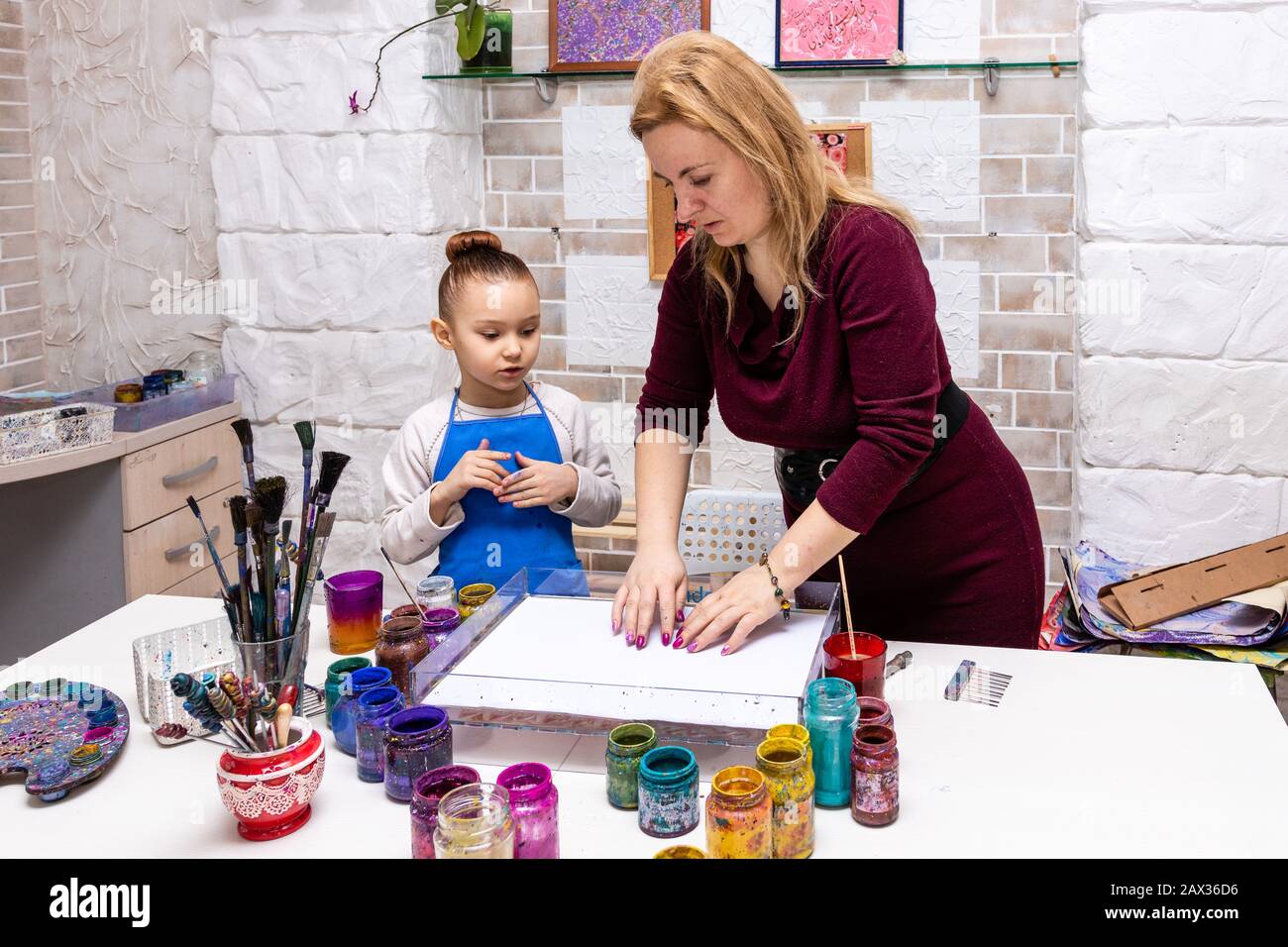 female teacher shows girl methods of transferring images on paper ...