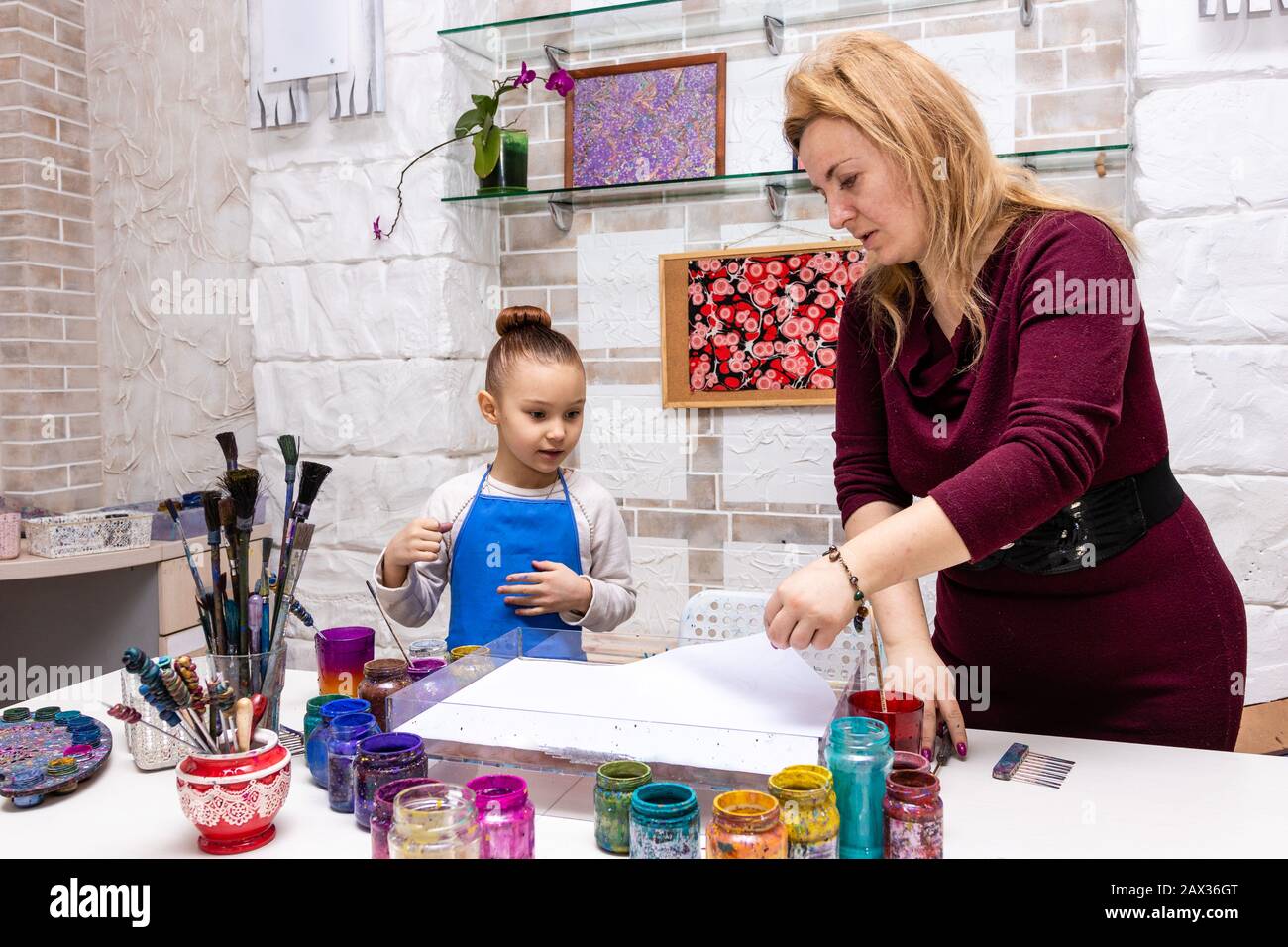 female teacher shows girl methods of transferring images on paper ...