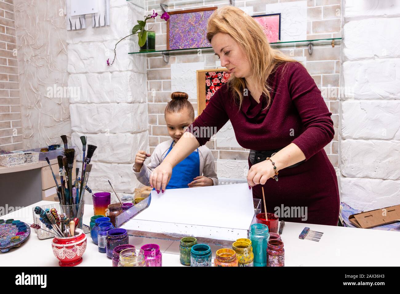 female teacher shows girl methods of transferring images on paper ...