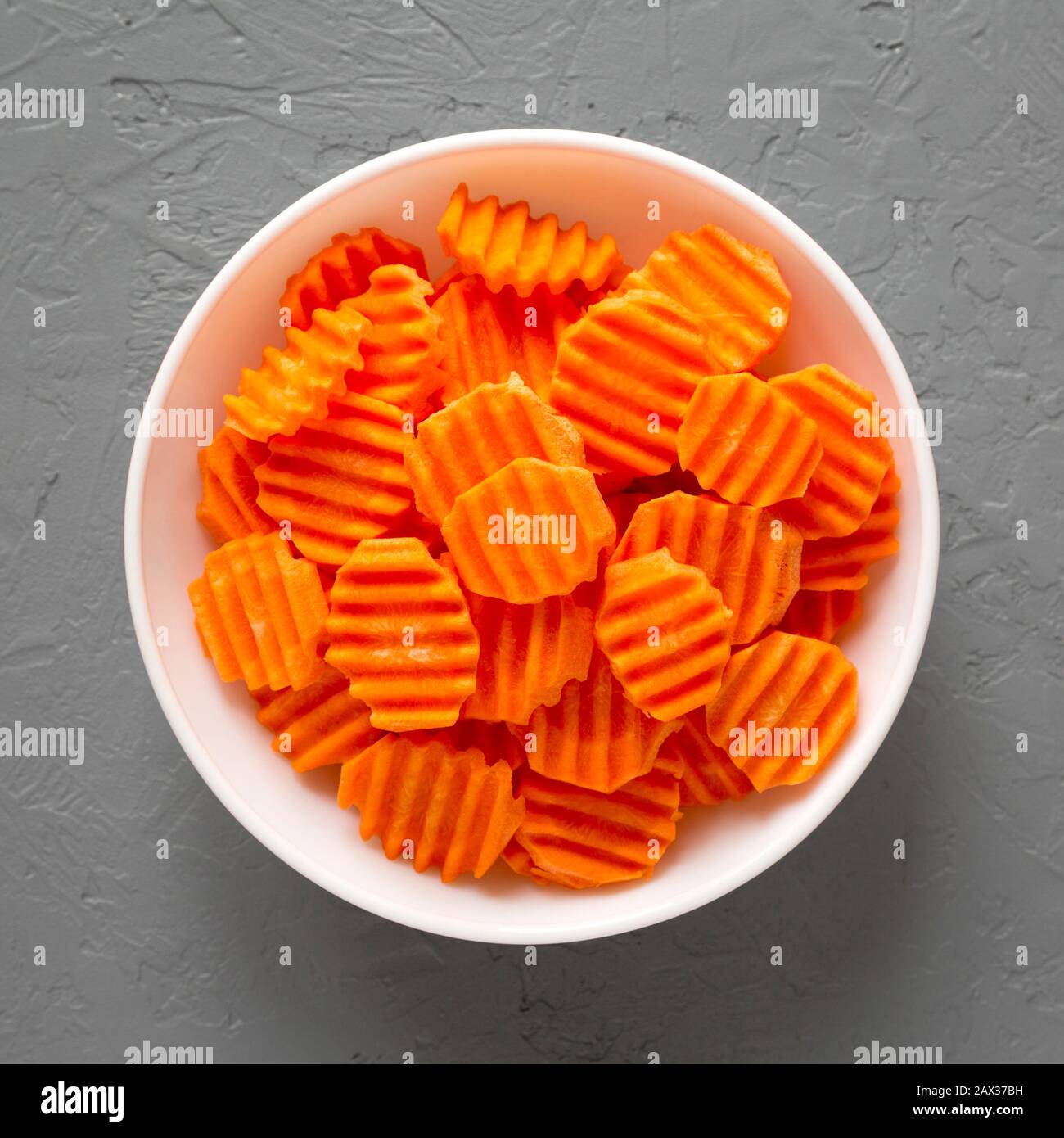 Fresh Raw Organic Carrot Chips in a white bowl over gray surface, top ...