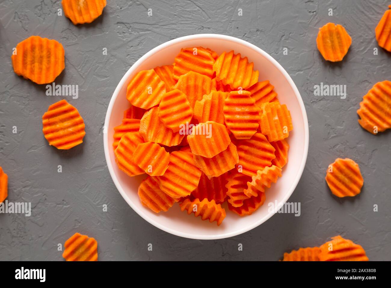 Fresh Raw Organic Carrot Chips in a white bowl over gray surface, top ...