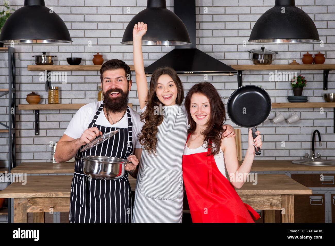 Together is more tasty. Mom dad and daughter aprons in kitchen. Cooking ...
