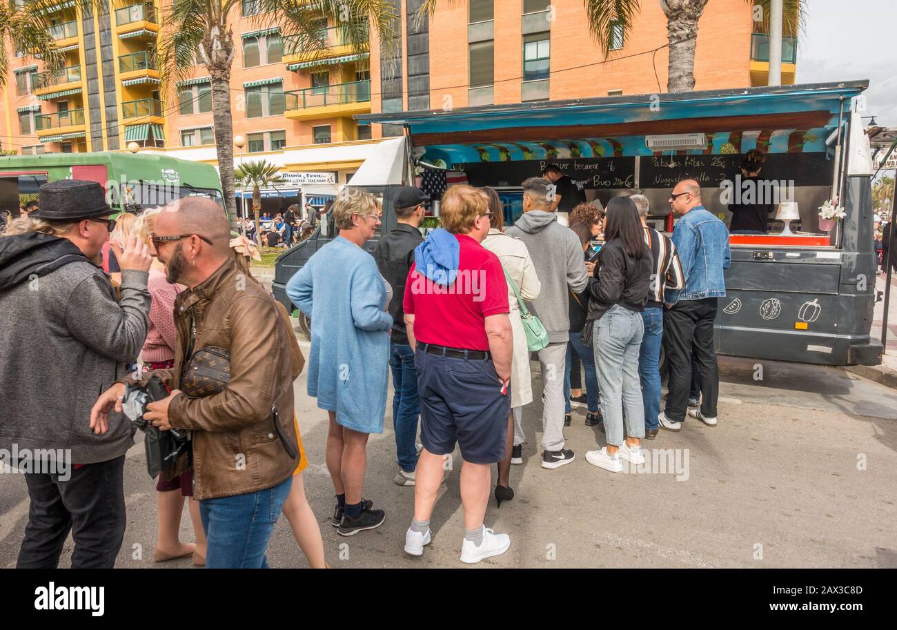 People lining up at a food truck serving hamburgers on street. Spain ...