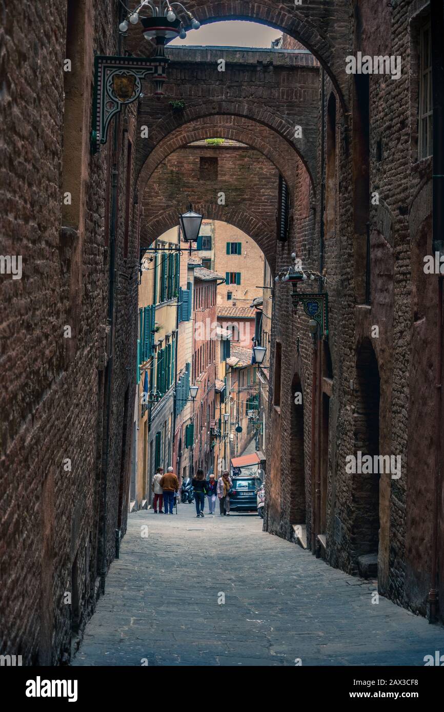 Scenic view through arch with medieval brick buildings Siena, Tuscany ...