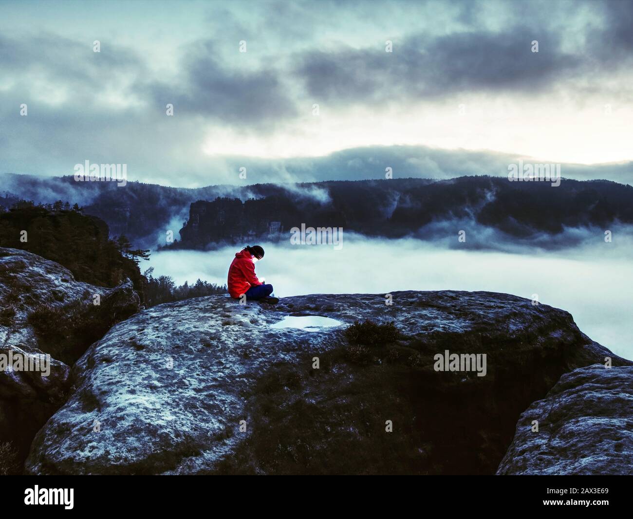 Back view of woman with flashlight standing on rocky bank, sharp light ...