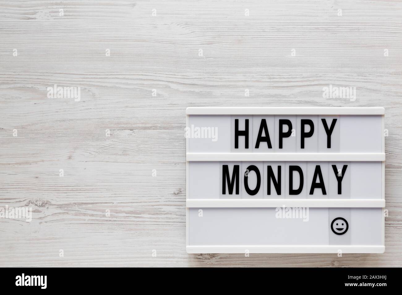 'Happy monday' words on a lightbox, clipboard with blank sheet of paper ...