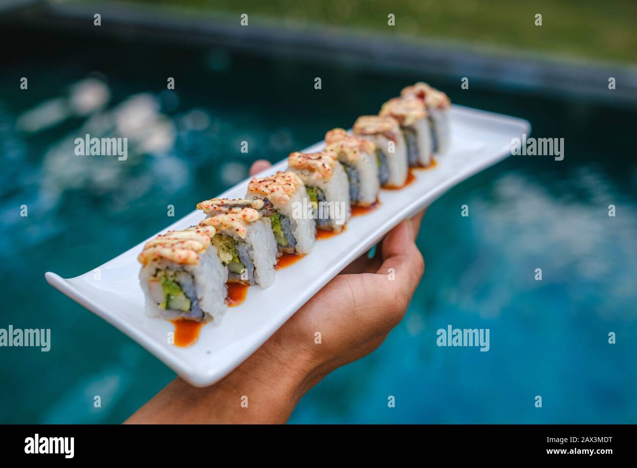Holding a tray of sushi in front of the pool Stock Photo - Alamy