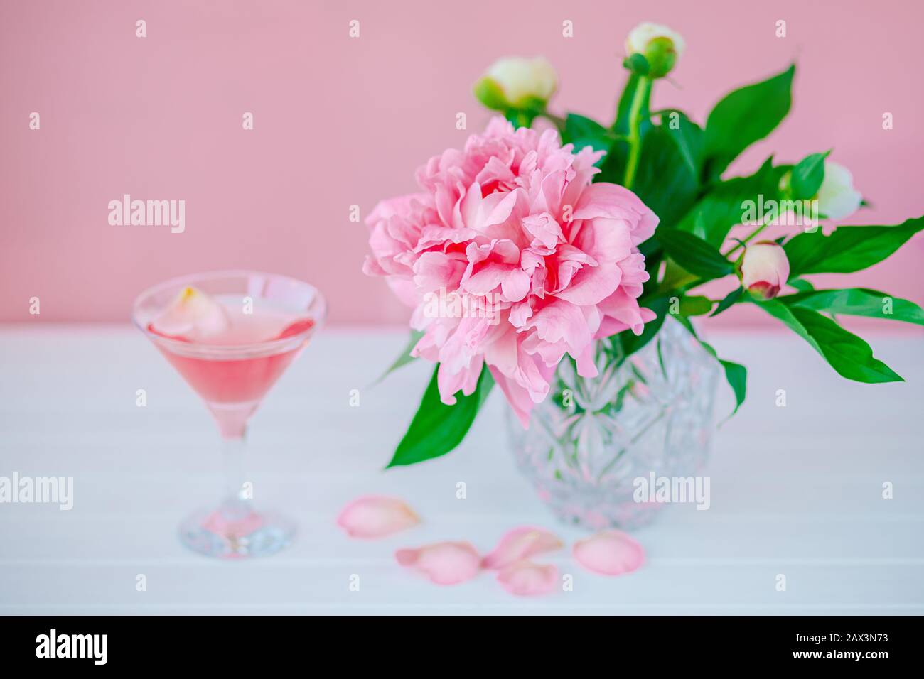 Good morning. Pink peonies in a crystal vase on a pink wood background ...