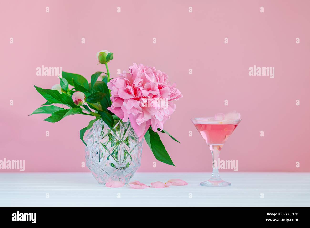 Good morning. Pink peonies in a crystal vase on a pink wood background ...