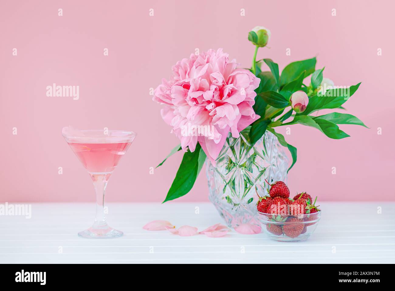 Good morning. Pink peonies in a crystal vase on a pink wood background ...