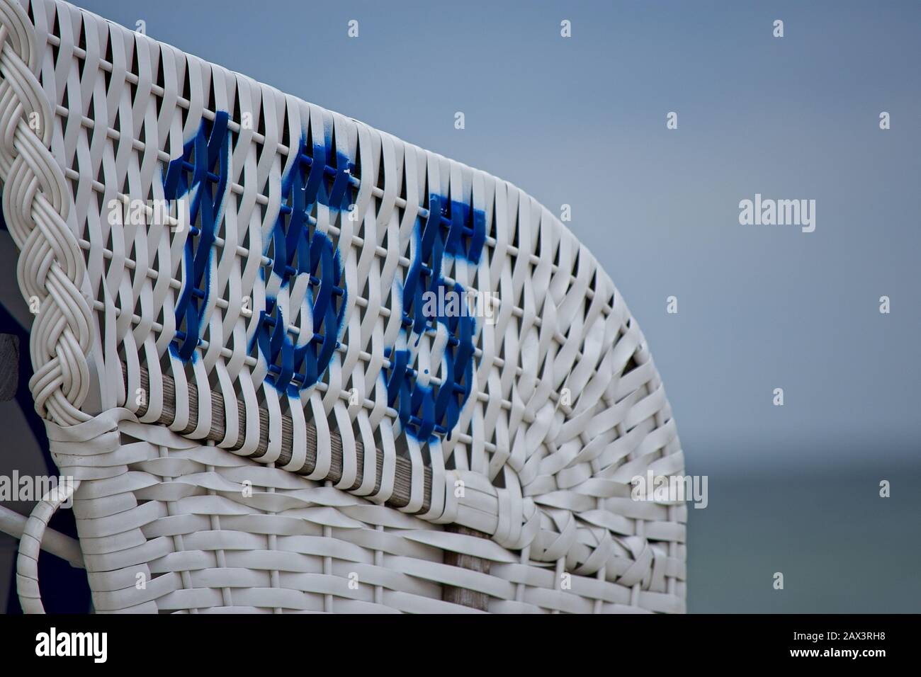 Number 155 stencilled in blue on a white painted wicker beach chair ...