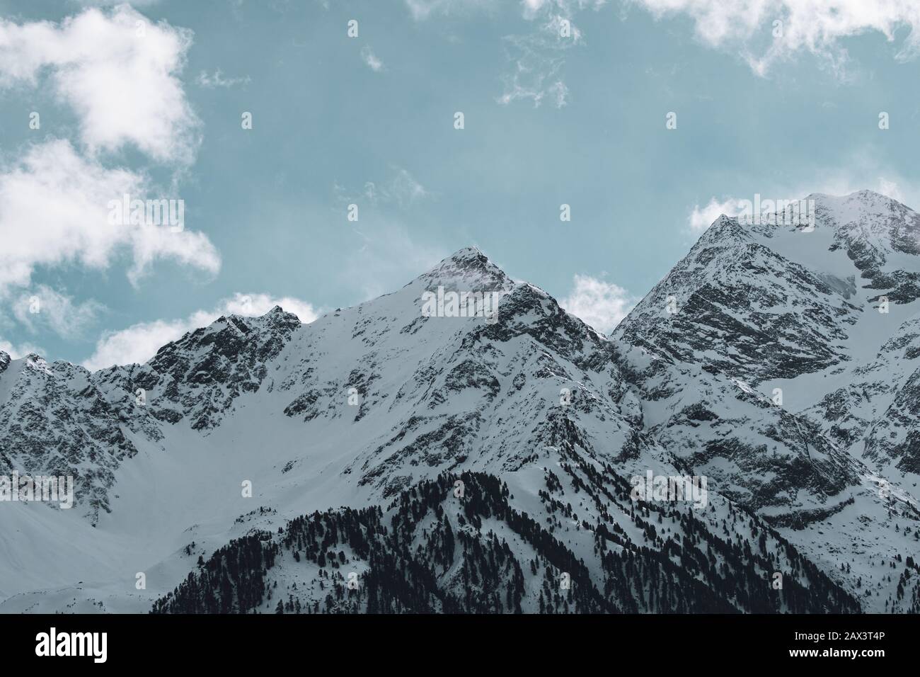 Picture of rocky mountains covered in the snow under a cloudy sky and ...