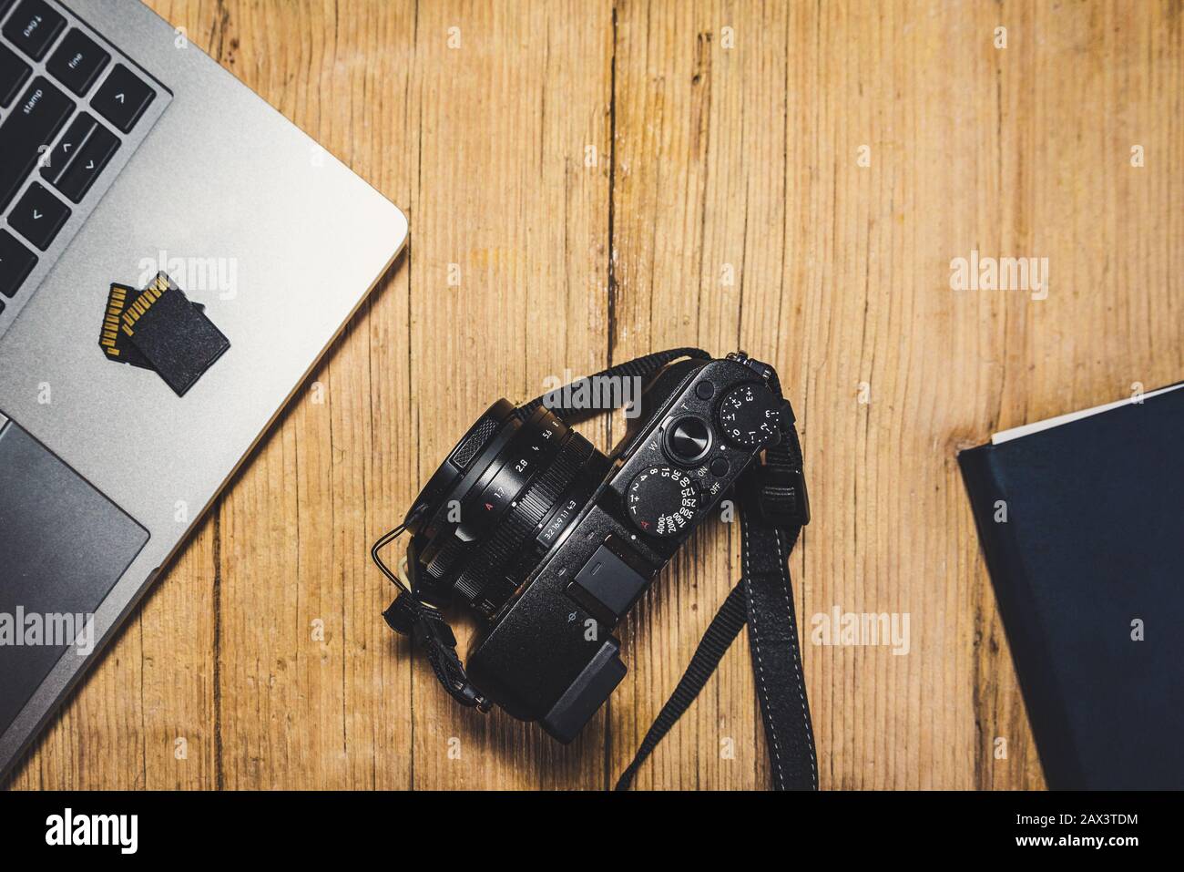 Wooden desk table with camera, laptop, memory cards and clipboard. View ...
