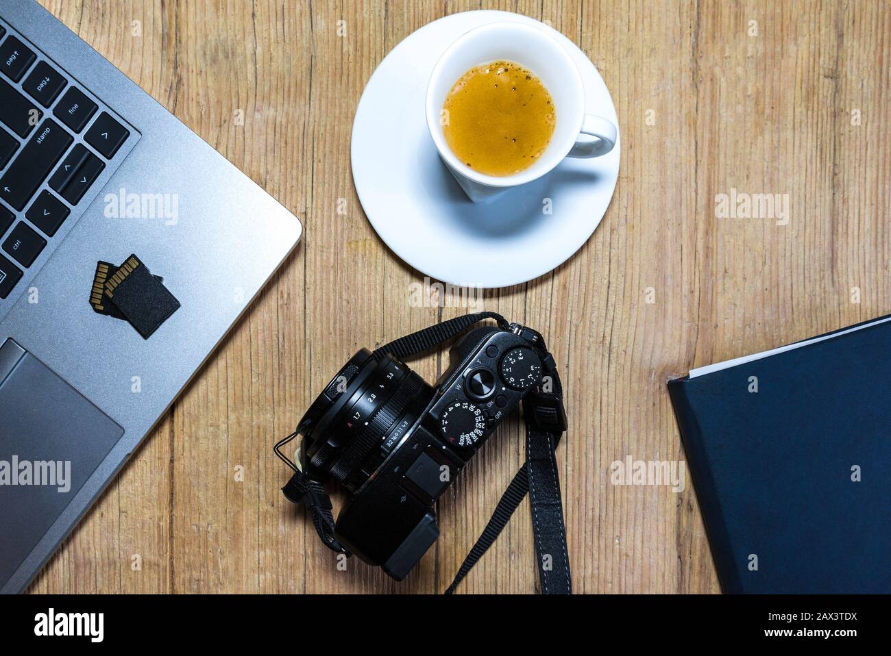 Wooden desk table with camera, laptop, memory cards, espresso cup and ...